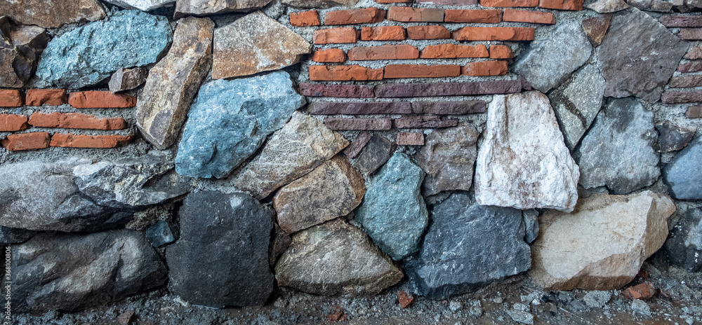 A mosaic of stones and bricks. The wall is made of natural boulders and ...