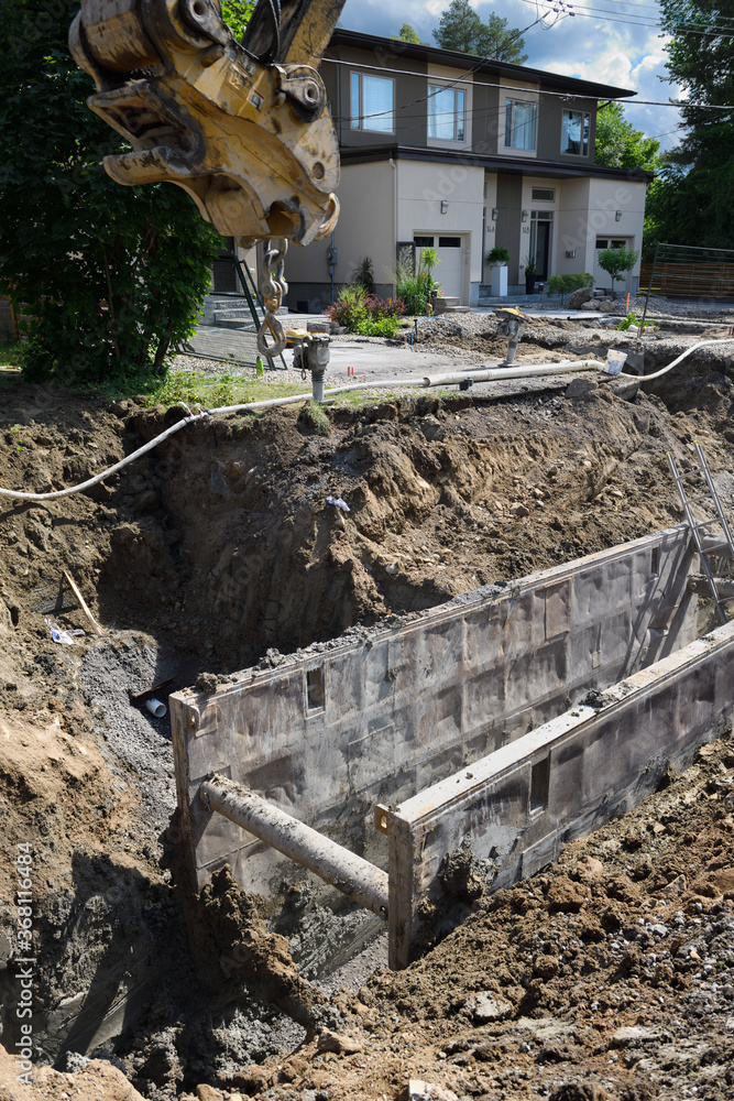 Modern house next to deep trench box for installation of new sewer ...