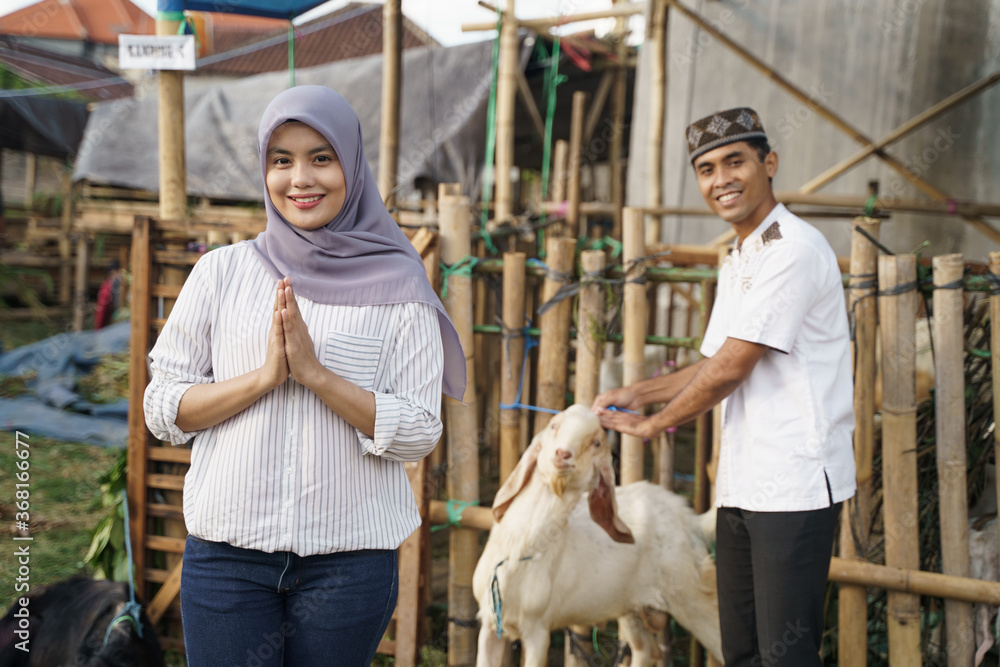 portrait of young muslim woman with goat for idul adha qurban sacrifice ...