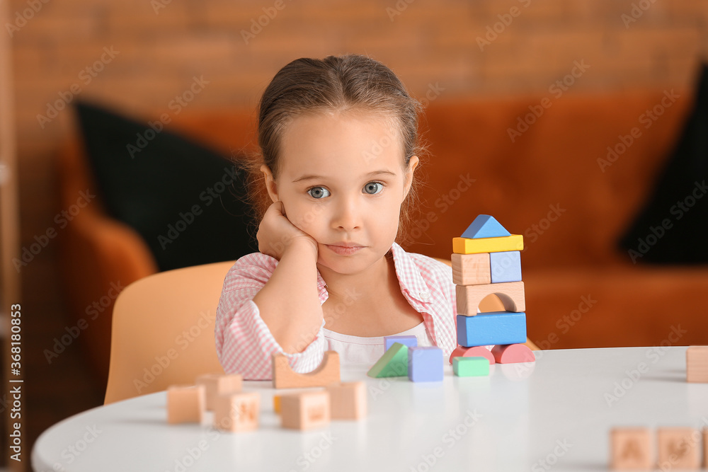 Sad little girl with autistic disorder playing with blocks at home ...