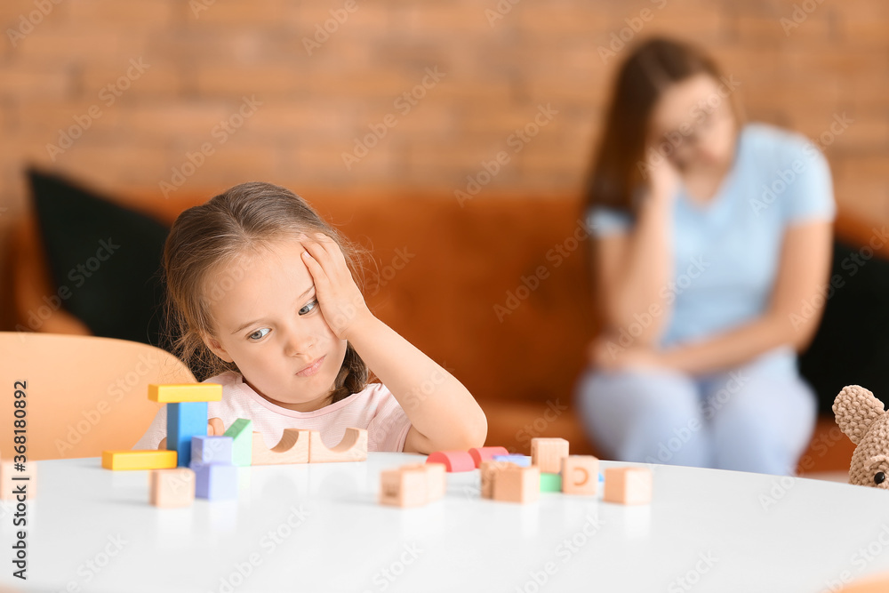 Sad little girl with autistic disorder playing with blocks at home ...