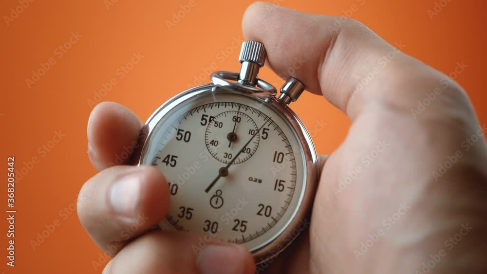 Vidéo Stock Male hand holding analogue stopwatch on orange color ...