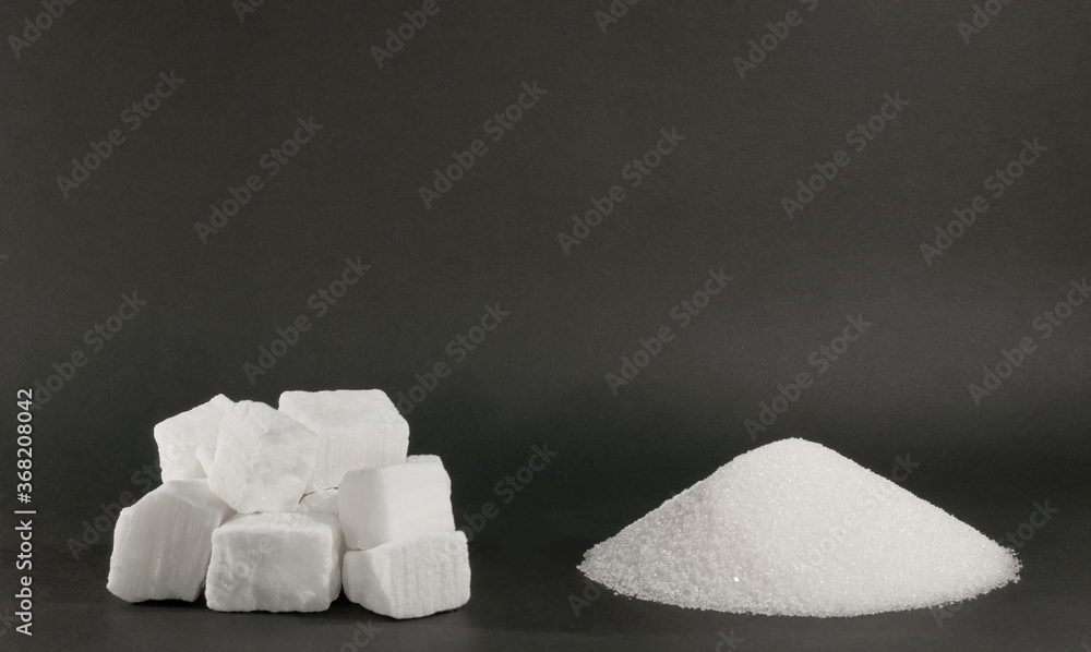 lump and granulated sugar on a black background, a source of glucose ...