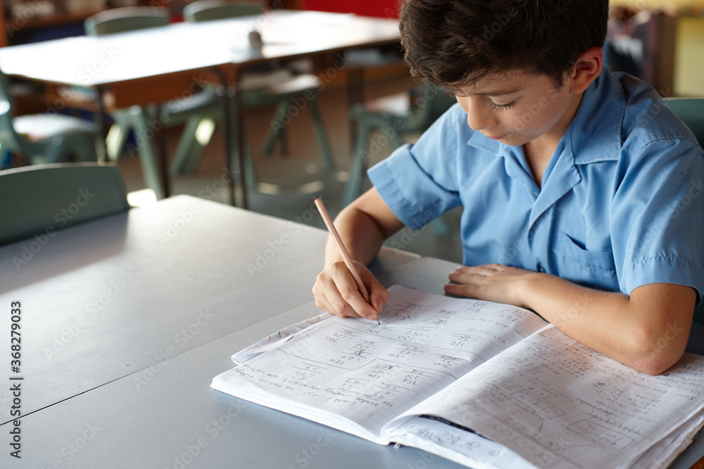 Young school boy doing maths in class Stock Photo | Adobe Stock