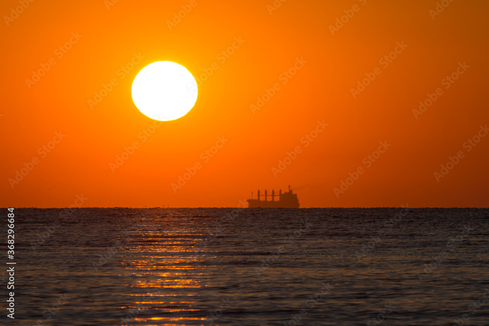Beautiful ocean sunrise, cargo container ship on the horizon. The sun ...