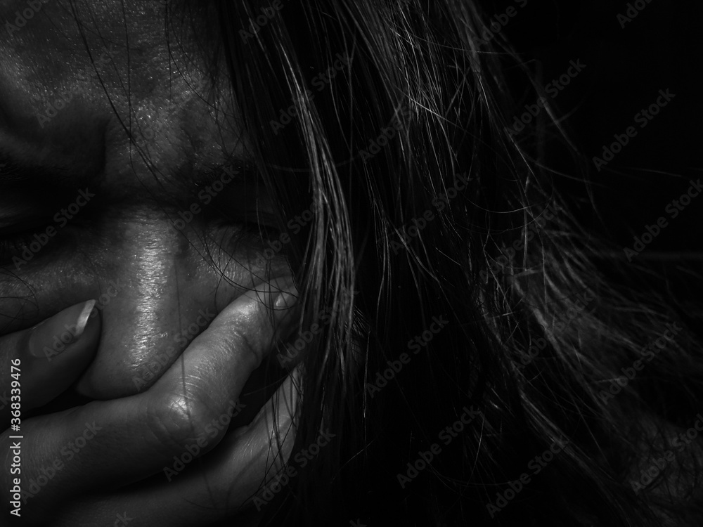 Scared woman crying on dark background - Covering the sad face with the ...