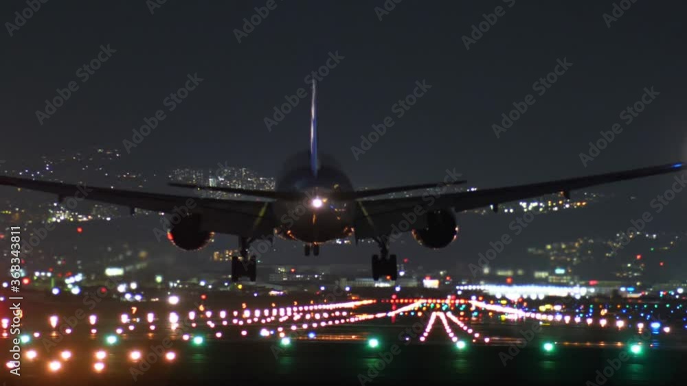 Aircraft landing at night time, telephoto perspective, bright lines of ...