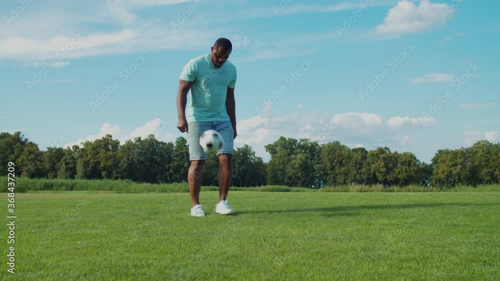 Handsome african man in casual clothes bouncing soccer ball on legs on ...