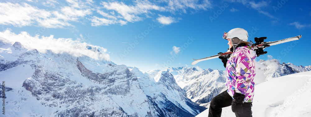 Profile view of teen girl skier on top of the mountain stand, hold ski ...
