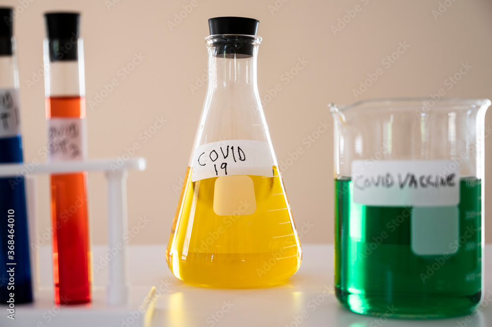 Covid-19 vaccine research. Test tubes, flask and beaker with colored ...