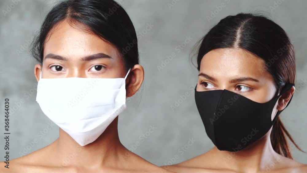 Closeup faces ot two beautiful Asian women posing in medical face mask ...