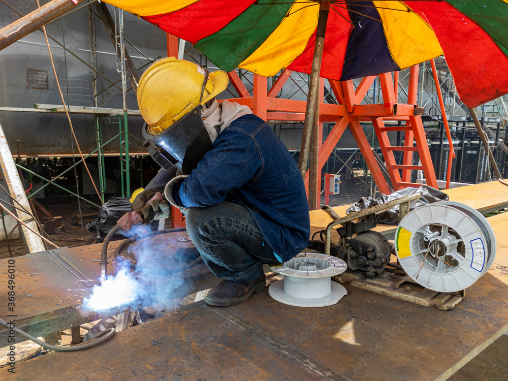 The welder is welding add joint a steel plate with process Flux Cored ...