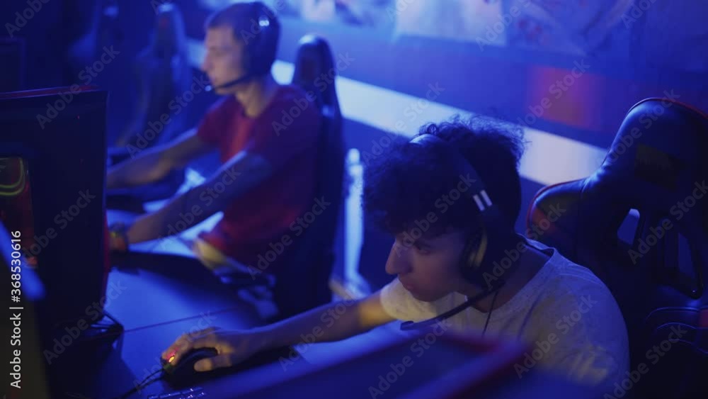 Two friends plays in a computer club, an online game. They are sitting ...