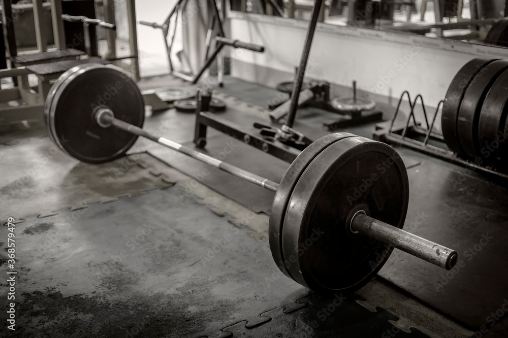 A rusty olympic size barbell loaded with plates on rubber matting. In ...