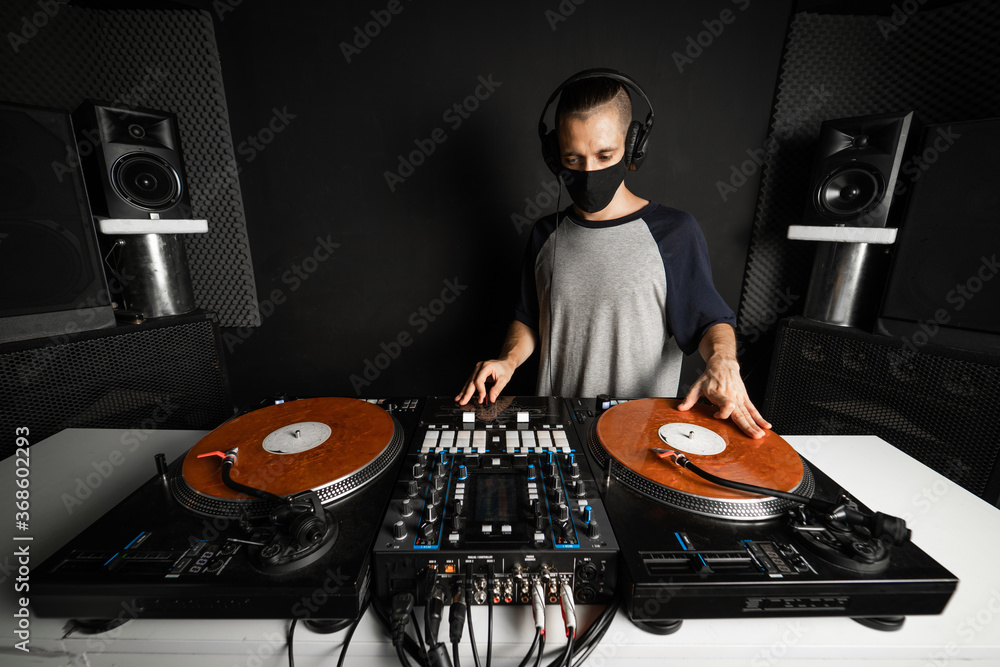 Dj con mascarilla de tela negra reutilizable haciendo scratching con ...