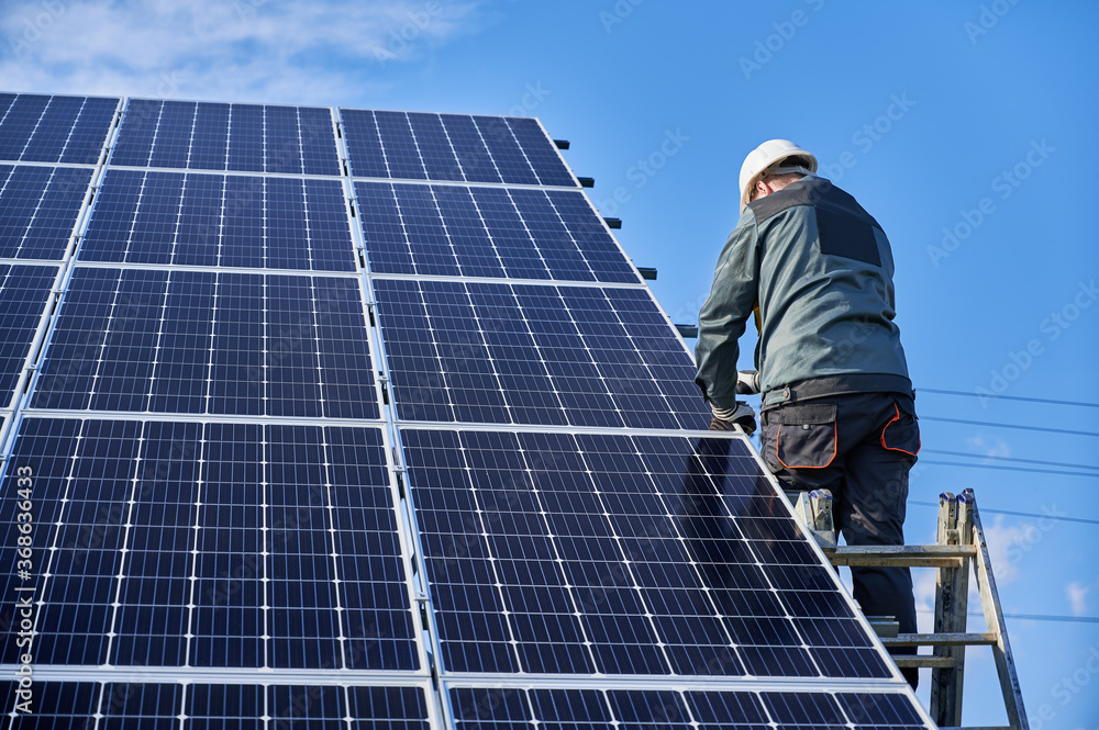Back view of man technician standing on ladder and installing ...