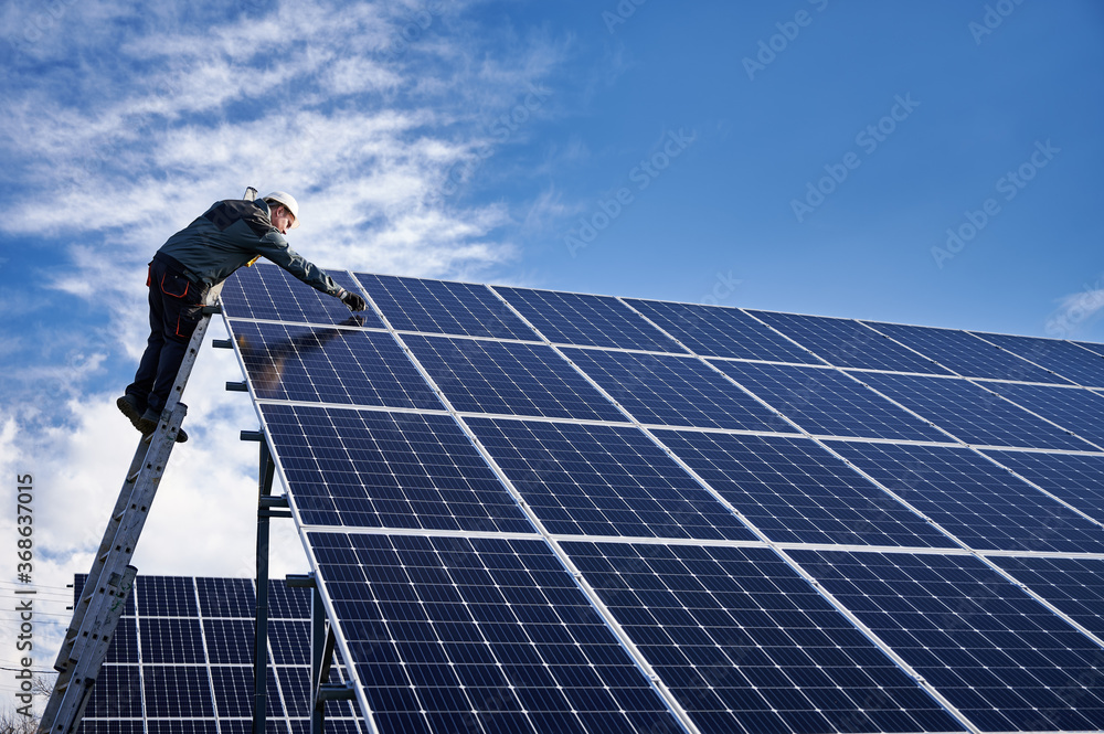 Male worker in white safety helmet standing on ladder and repairing ...