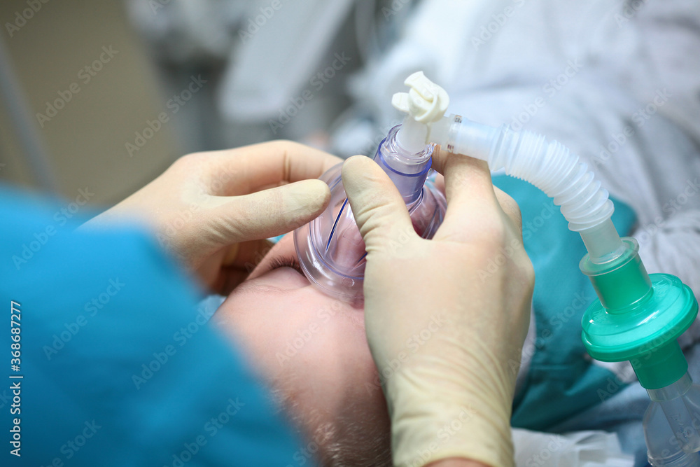 Foto de The anaesthetist holds a breathing mask on the child's face ...