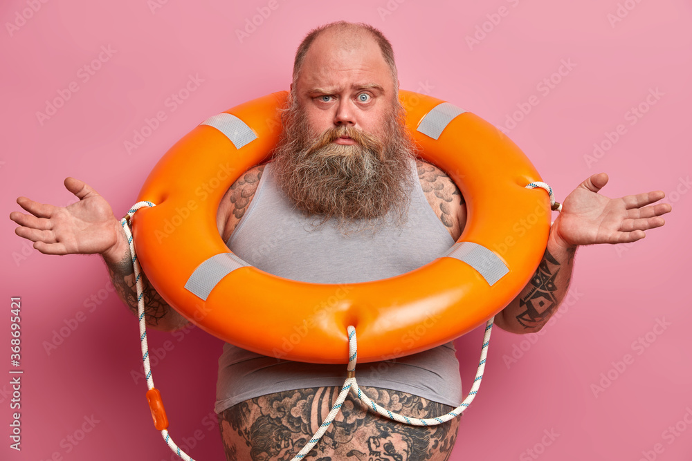 Image of puzzled overweight man spreads hands, poses with inflated ...
