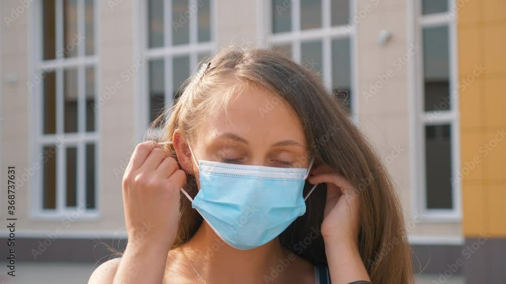 A young girl puts on a medical mask. The girl is breathing deeply in a ...