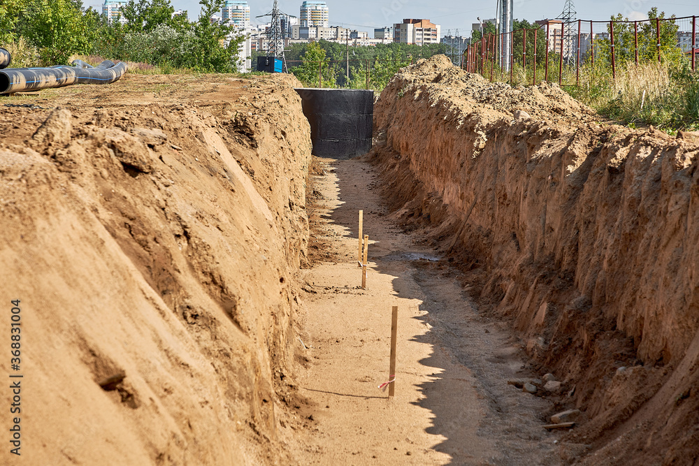 Trench for installation of water pipes.The reinforced concrete wall is ...