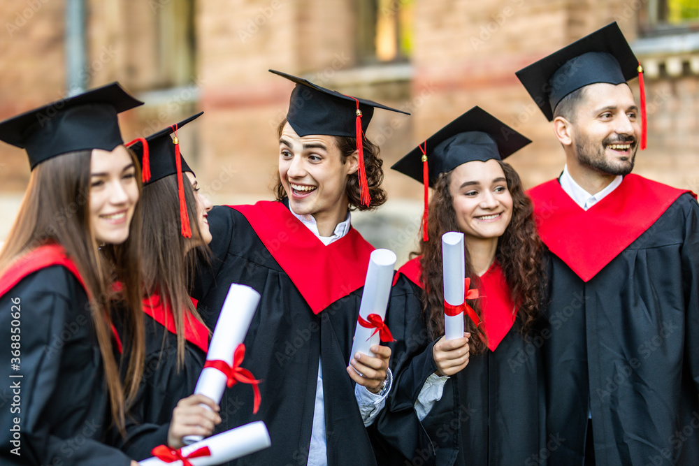 Graduates embrace, enjoy and look at the camera on the graduation ...