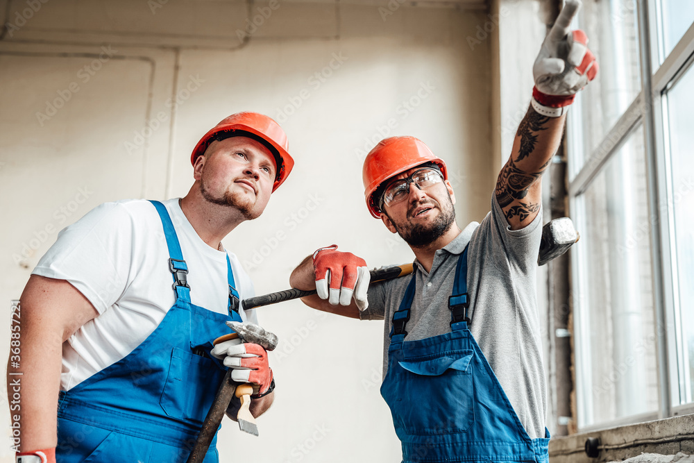 Fat and thin workers discussing the upcoming work, one of them holding ...