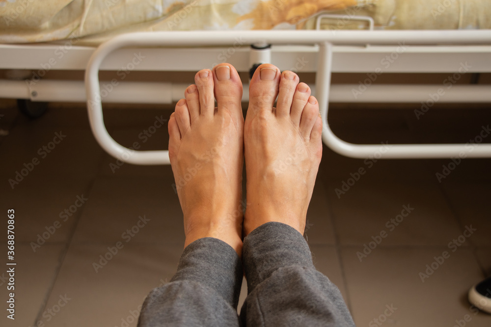female legs barefoot in limbo against the background of a tile of a ...