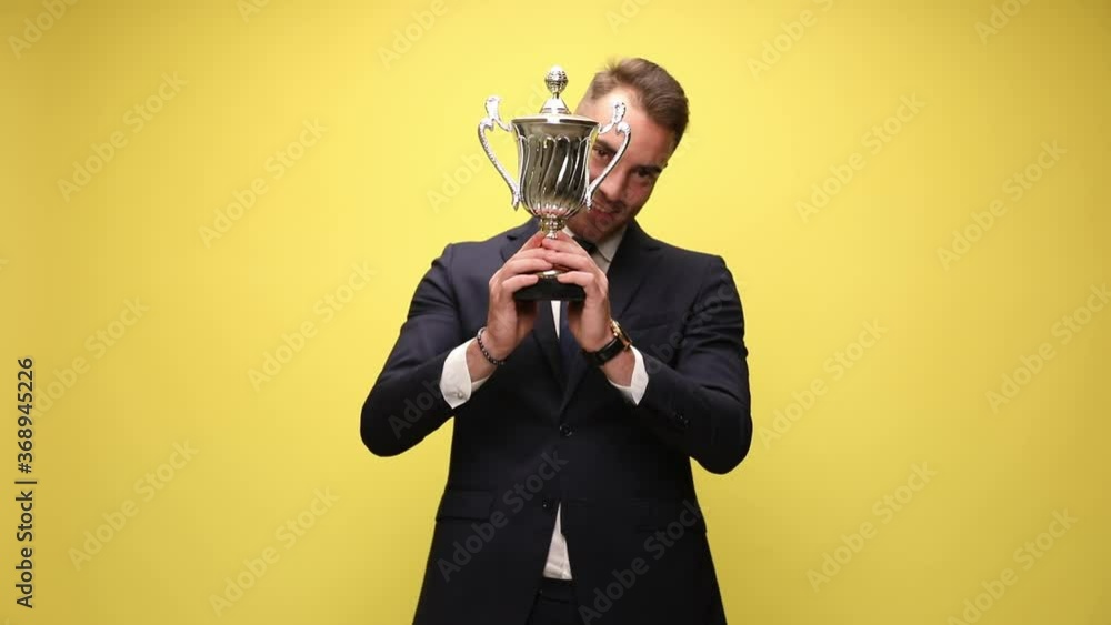 Vidéo Stock goofy young businessman hiding behind silver trophy ...