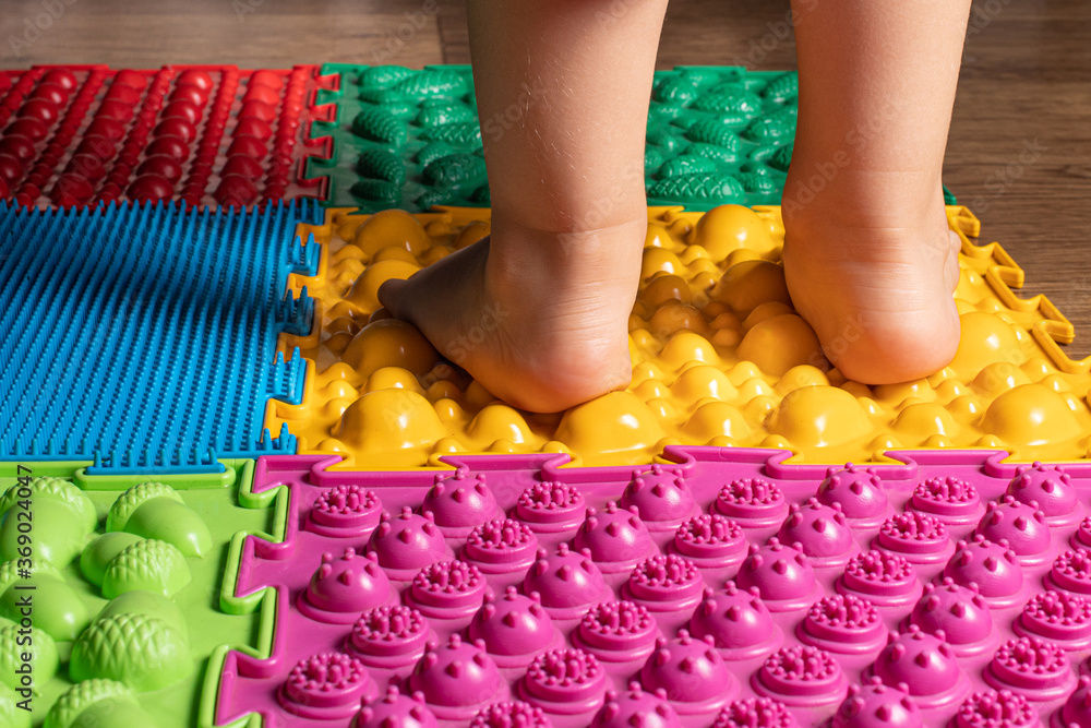 The legs of a small child on orthopedic mats. Bright surfaces for ...