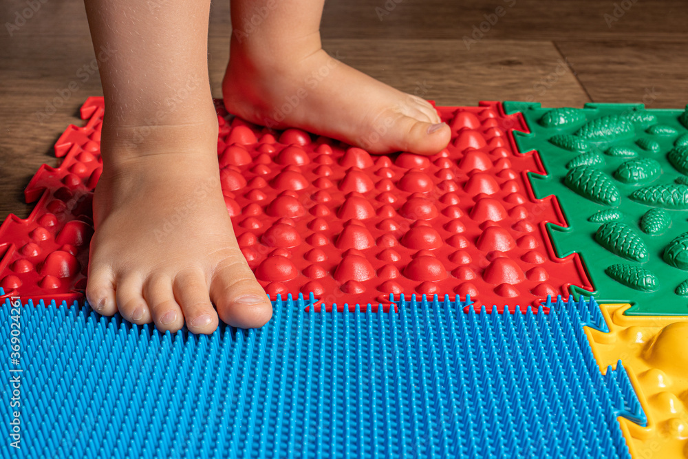 The legs of a small child on orthopedic mats. Bright surfaces for ...