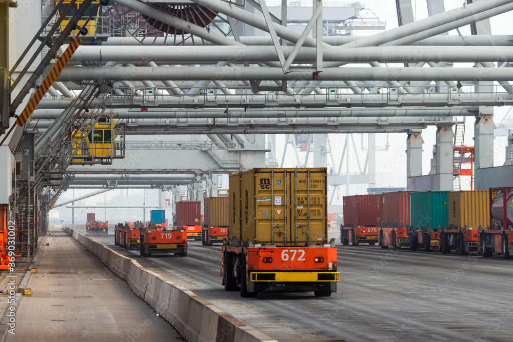 Automated vehicles moving shipping containers to and from gantry cranes ...