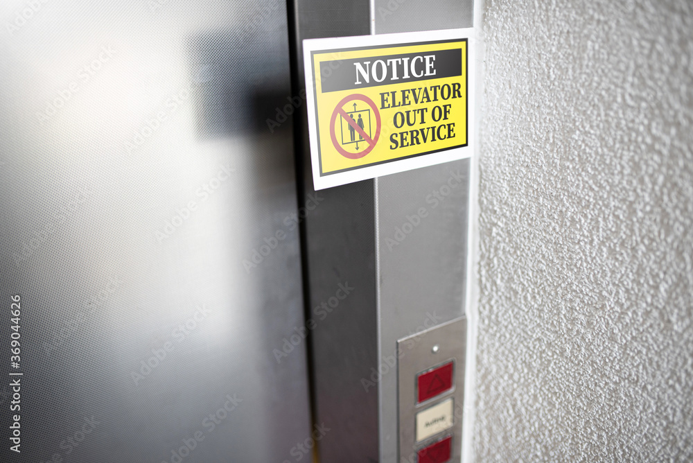 yellow elevator out of service notice sign attached to elevator door ...