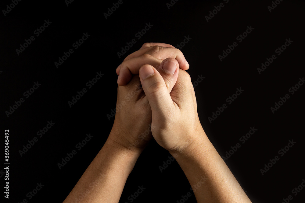 The man's hand that clasped his hand praying has a black or dark ...