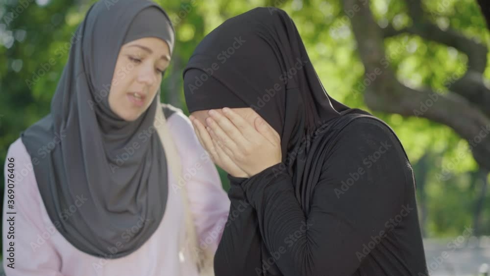 Desperate Muslim woman in hijab crying as friend calming her down ...