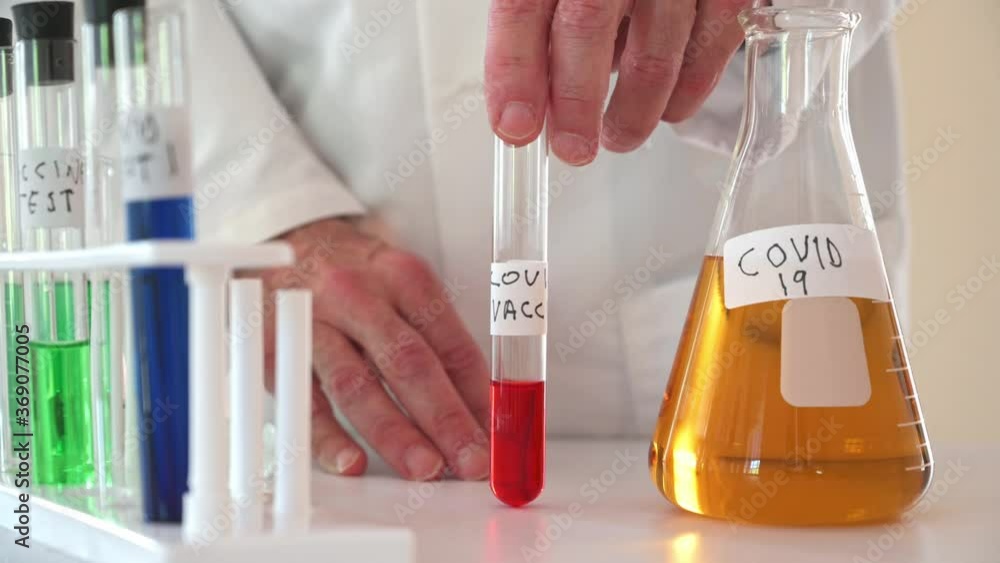 Man removes test tube labeled Covid Vaccine from test tube holder ...