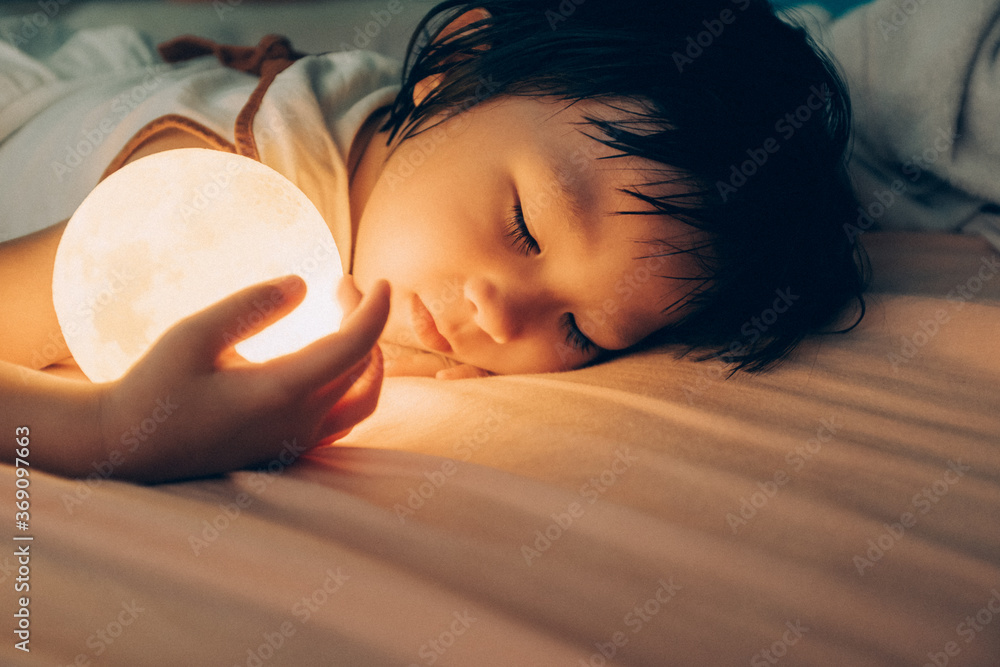 Little girl lying in bed holding a lamp Stock Photo | Adobe Stock