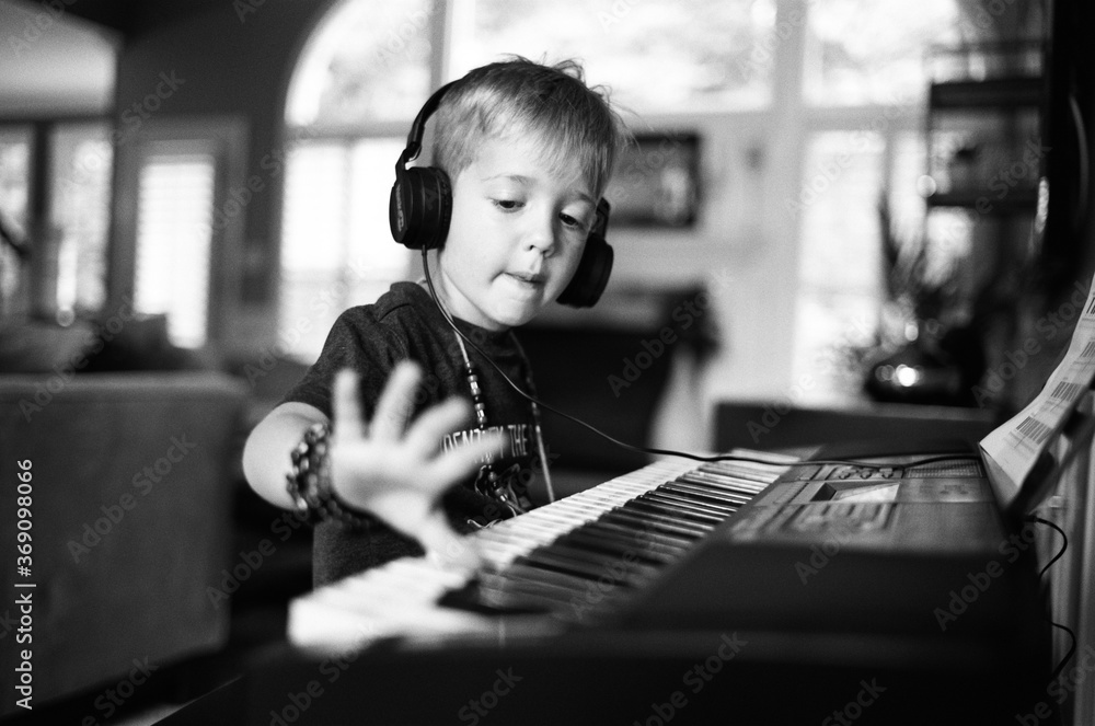 Cute young boy playing a keyboard piano Stock Photo | Adobe Stock