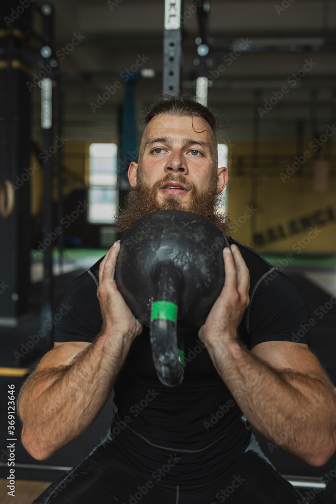 Strong and healthy man working out with a kettlebell , inside a ...