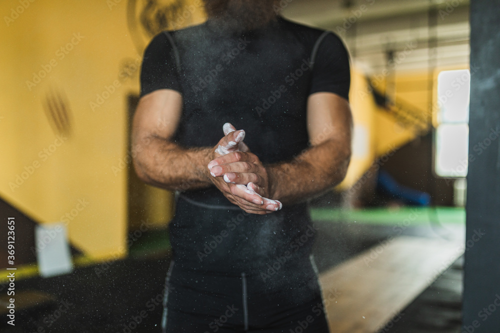 Strong and healthy man using talcum in his hands, inside a crossfit gym ...