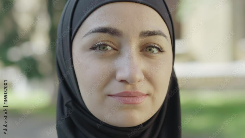 Close-up face of young beautiful woman in traditional hijab looking at ...