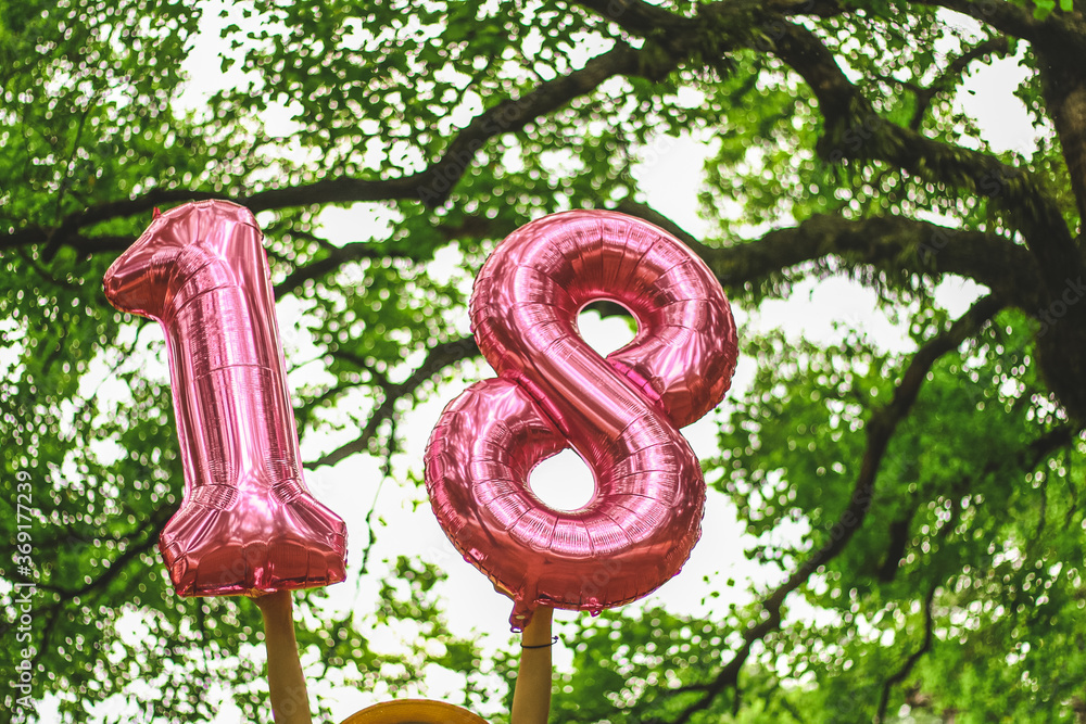 a girl is holding of two balloons. the balloons say eighteen because it ...