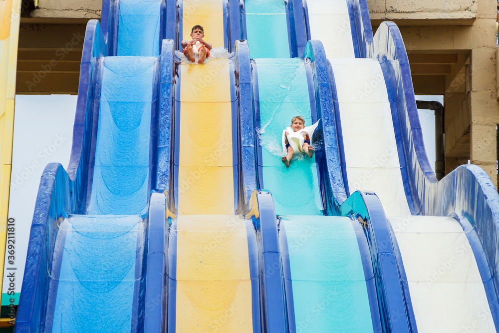 Two brothers are swiftly descending the slide in the water park. Family ...