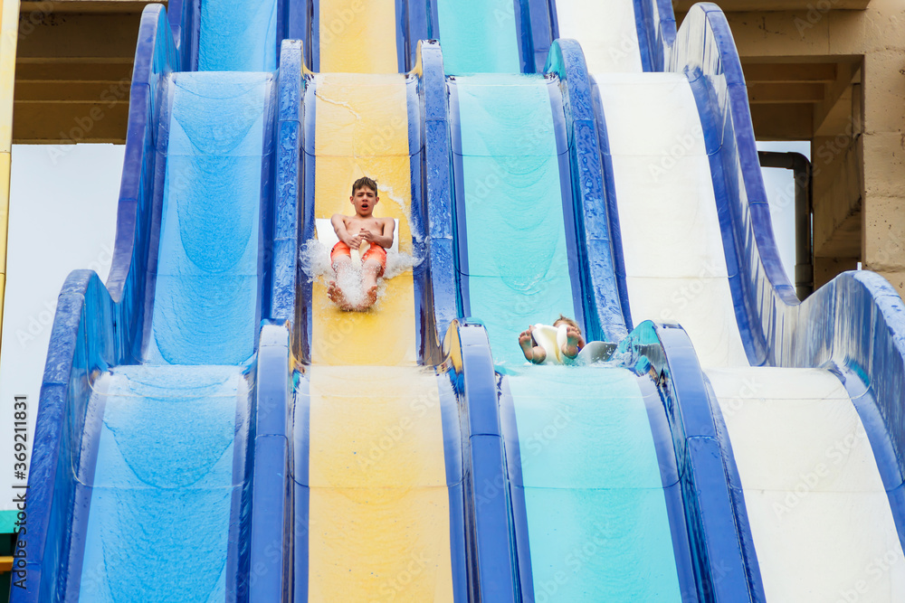 Two brothers are swiftly descending the slide in the water park. Family ...