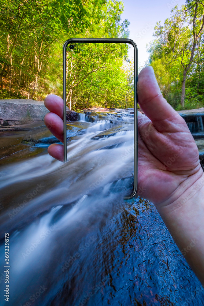 Hand holding smart phone. Pop Up 3d. a small waterfall and its river ...