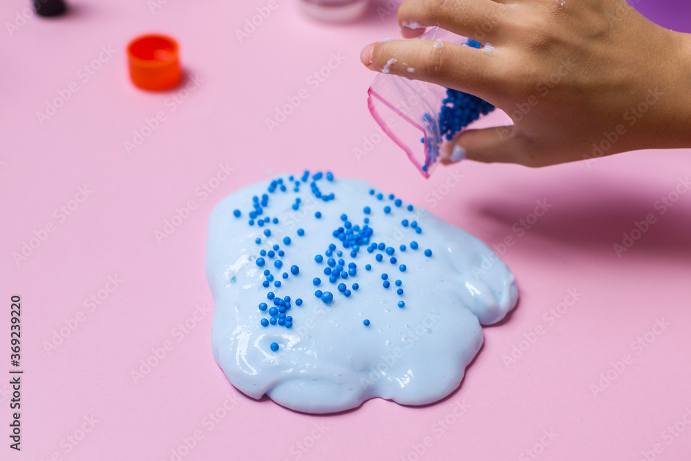 Blue slime on a pink background. Children make a slime toy at home ...