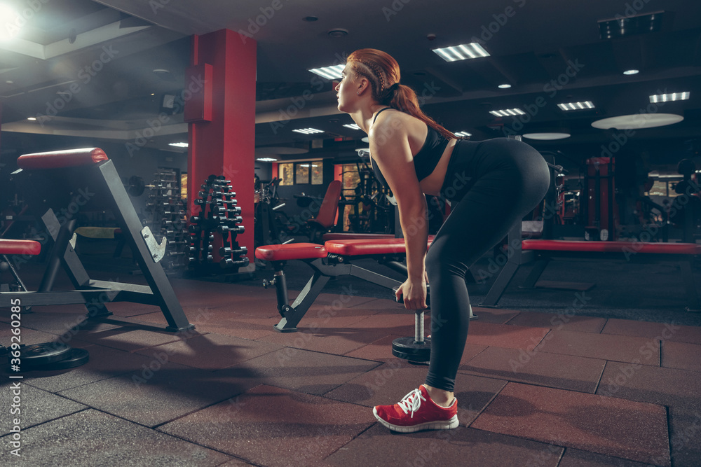Sit up. Young muscular caucasian woman practicing in gym with equipment ...