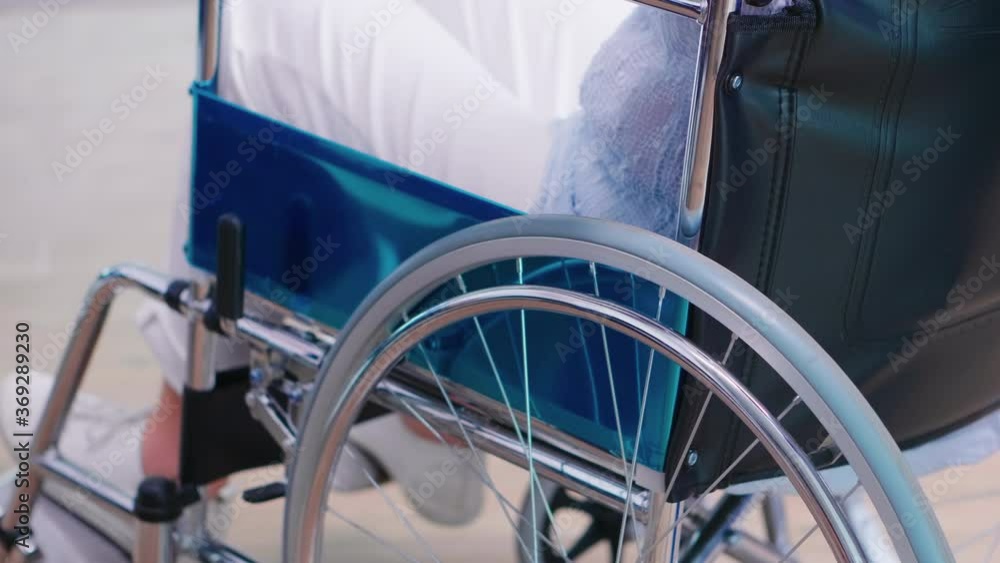 Disabled old woman holding hands on chair wheell in hospital hallway ...