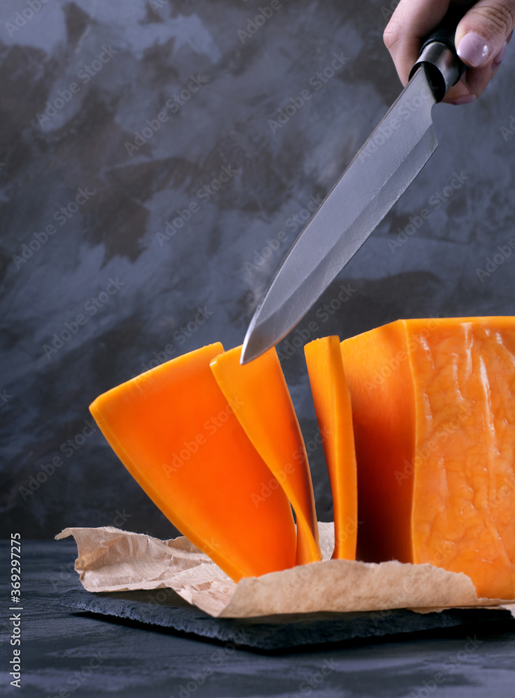 Red Cheddar cheese block cut into slices against the grey background ...