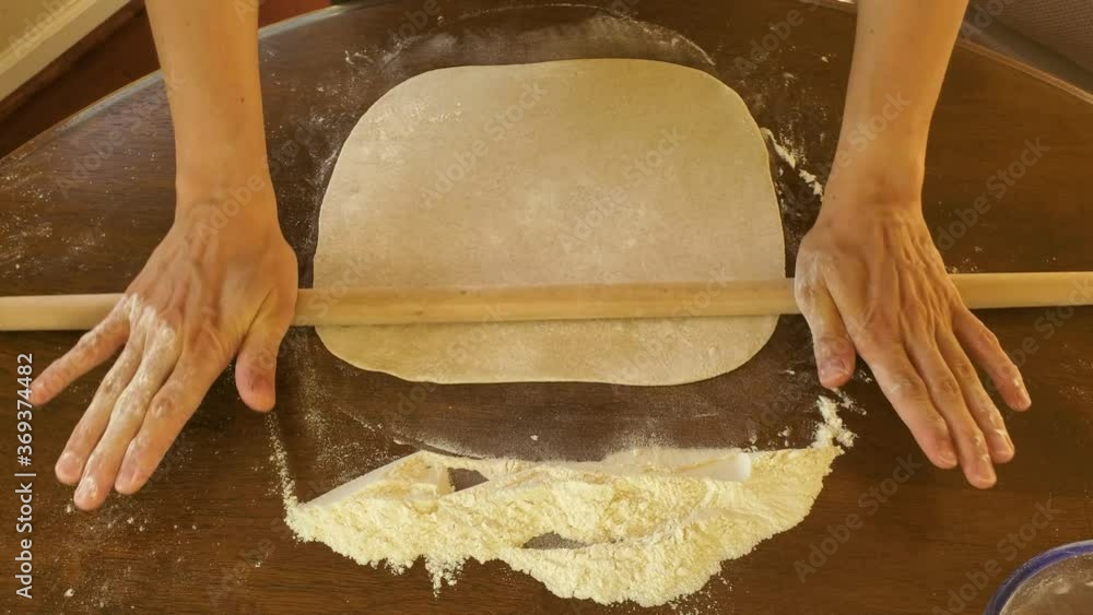 Video „A chef is flatting a dough ball using a traditional long and ...